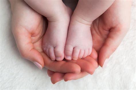 Newborn ноги младенца в руках мати Уход за детями чувствуя безопасен