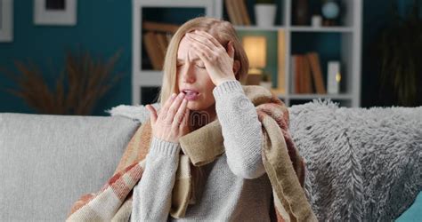 Hustende Frau Während Der Sitzung Auf Der Couch in Der Warmen