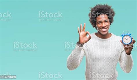 아프리카 미국 남자 지주 빈티지 알람 시계 위에 고립 된 배경 하 고 Ok 기호 손가락으로 우수한 상징 벽 시계에 대한 스톡