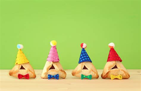 푸 림 축 하 개념 나무 테이블과 녹색 배경 위에 귀여운 광대 모자와 전통적인 Hamantaschen 쿠키 귀 부분에 대한 스톡