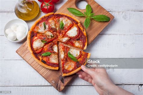 흰색 나무 테이블에 맛 있는 이탈리아 피자 마르게리타의 근접 촬영 최고의 볼 수 있습니다 여자의 손은 피자의 조각 녹기에 대한