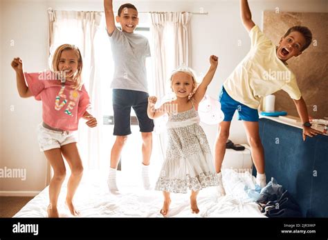 Theyve Got Endless Energy Portrait Of Little Siblings Jumping On A Bed