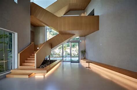 라이트 우드 계단과 매립 조명이 조화를 이루는 미니멀 라운지 입구 공간 사진