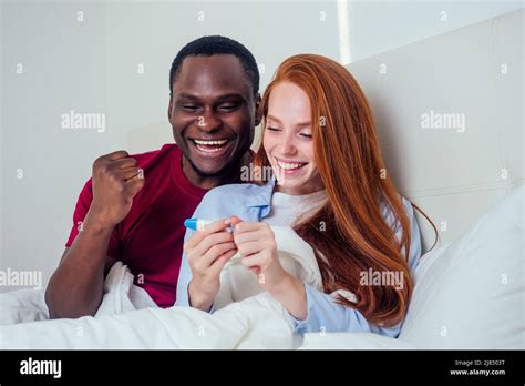 Mixed Race Couple Watching Pregnancy Test In Bed Redhaired Ginger