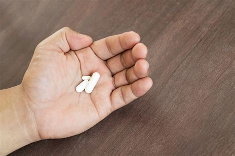 여러 알약을 복용 손을 가까이 남자는 나무 테이블에 마시는 물 컵 유리를 들고 손에 약을 약물 복용 약물 건강 관리 의료 개념을 중지합니다 개념에 대한 스톡 사진 및 기타