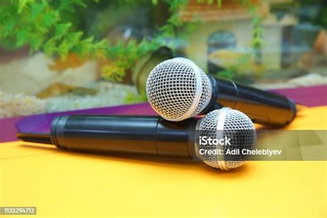 노란색 배경 위에 고립 된 두 개의 은색 마이크 회의 테이블에 두 개의 무선 마이크가 있습니다 공연에 대한 스톡 사진 및 기타