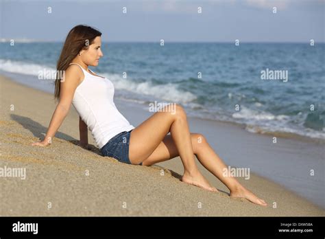 Beautiful Woman Sitting On The Sand Of The Beach Watching The Sea With