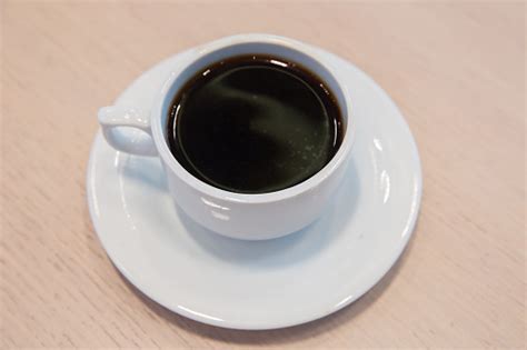 화이트 컵 화이트 소스커피 카페 흐림 배경에서 테이블에 뜨거운 커피 한 잔 흰색 도자기 컵에 커피 콩 장식 야생 허브 0명에