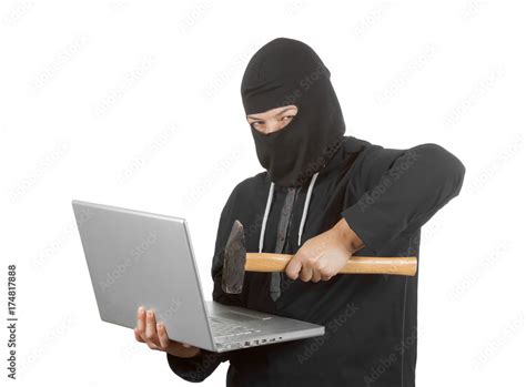 Criminal Woman Hacker Wearing Hood On In Black Clothes And Balaclava Destroy Laptop With Hammer