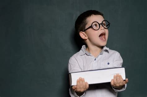 پسر مدرسه ای مبارک دانش آموز کوچولوی شاد با لیوان هایی که الف را در دست