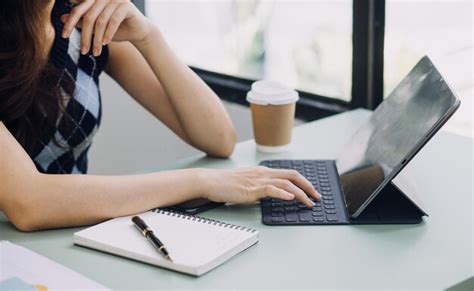 Mulher de negócios jovem sentada no escritório à mesa e usando smartphone na mesa está o laptop