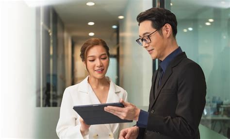 사무실에서 회의하는 동안 그녀의 관리자에게 태블릿을 보여주는 웃는 아시아 사업가 무료 사진