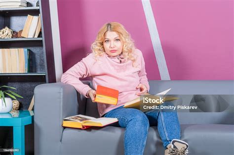 슬픈 외로운 소녀는 두꺼운 책의 더미와 소파에 앉아있다 카메라를 봅니다 가정 생활에 대한 스톡 사진 및 기타 이미지 가정 생활 거실 고독 부정적인 감정 표현 Istock