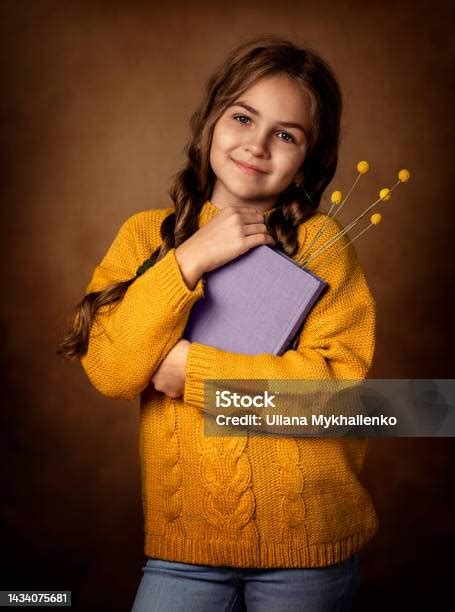 Seorang Gadis Dengan Sweter Kuning Memegang Bukubuku Tua Di Tangannya