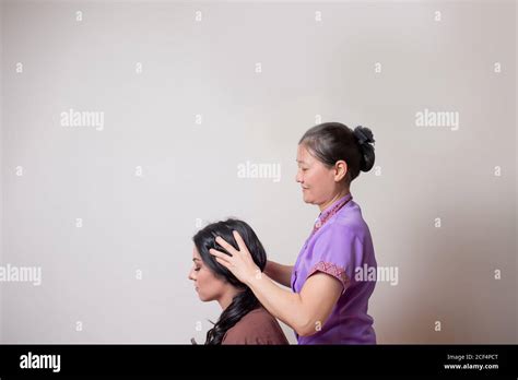 Asian Masseur Doing Thai Head Massage For Caucasian Woman In Spa Salon
