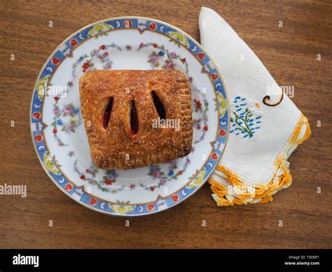 A Raspberry Filled Pastry Served On A China Plate With Blue Rim And An
