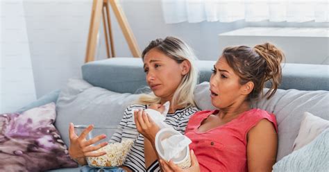 두 명의 가장 친한 친구가 침대에서 슬픈 영화를 보고 만지고 울고 있다 소녀들은 팝콘과 Tv 리모컨을 들고 텔레비전에서 화면