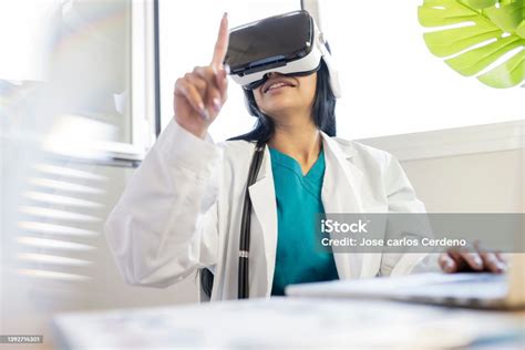 제복을 입은 여성 의사가 시각 현실 안경을 쓰고 사무실에 앉아 있습니다 20 24세에 대한 스톡 사진 및 기타 이미지 20 24세 3차원 형태 Stem 주제 Istock