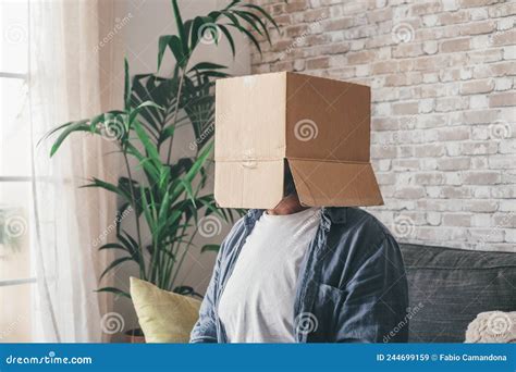 Mature Man Wearing Empty Carton Box Sitting On Sofa In The Living Room Of House Caucasian Guy