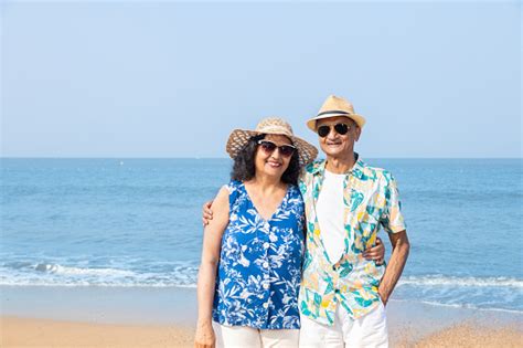 손에 화려한 풍선을 들고 해변에서 함께 달리는 노인 인도 커플 휴가를 즐기고 해변에서 휴가를 보냅니다 공간을 복사합니다 은퇴