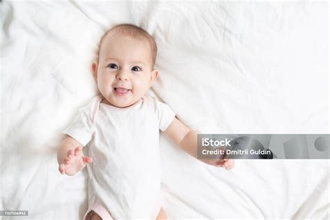 흰색의 매우 행복한 아기가 침대에 누워 카메라를 향해 손을 당기고 있습니다 밝은 배경에서 광고에 대한 스톡 사진 및 기타 이미지