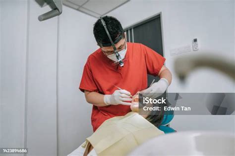 돋보기를 착용한 아시아 중국 남성 치과의사가 치과의사 사무실에서 여성 환자를 검사합니다 환자에 대한 스톡 사진 및 기타 이미지
