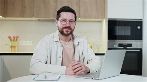 Man Sitting At Workplace While Tapping On Laptop And Gazing Directly At