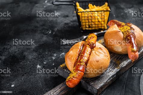 Deutsche Bockwurst 소시지를 프렌치 프라이와 카레 소스 카레 워스트와 함께 롤빵에 넣습니다 검은 배경 상단 보기