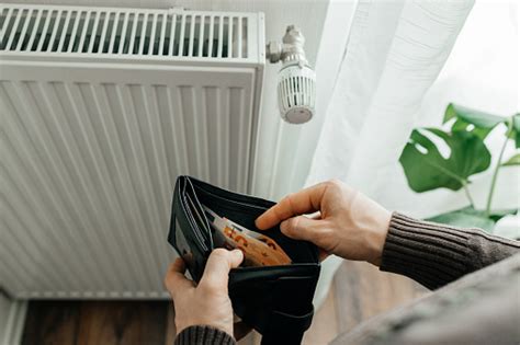 남자의 손은 라디에이터 옆에 돈이 든 지갑을 들고 있습니다 가스 및 에너지 가격 인상의 개념 유럽의 에너지 위기 가격에 대한