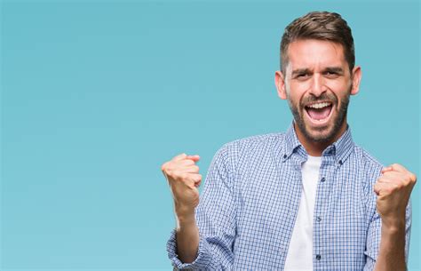 잘생긴 젊은이 매우 행복 하 고 흥분 무기와 우승자 제스처를 하 고 격리 된 배경 위에 흰색 T셔츠를 입고 웃 고 성공을 위한 비명 축 하 개념입니다 축하에 대한 스톡 사진