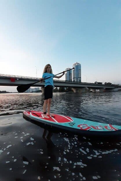 Premium Photo Athletic Girl Swims On A Sup Board Standing Smiling And Helping Herself With A