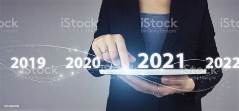비즈니스 새해 카드 개념 흰색 태블릿 은 회색 배경에 디지털 홀로그램 2021 년 기호와 사업가 손 12월 31일에 대한 스톡