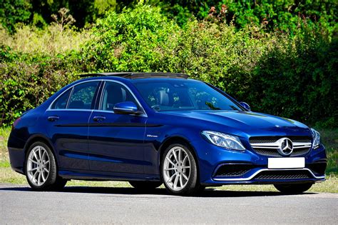 집 밖의 C 클래스 고급 승용차 고급 차량 고성능 고전적인 디자인 교통 기술 낮 네 개의 문 녹색 관목 도로 도시의 독일 공학 럭셔리한 매끄러운