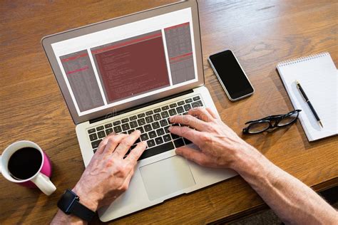 Hands Of Caucasian Male Programmer Sitting At Desk Using Laptop With Coding On Screen Stock