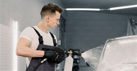 흐르는 물과 거품으로 세차 청소 거품으로 고압 스프레이를 들고 있는 젊은 세차 서비스 남성 직원의 측면 모습 세차장 역에