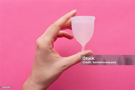 분홍색 배경 위에 고립 된 생리컵을 들고있는 젊은 여성의 얼굴없는 초상화 생리 친밀한 울음 소리의 날 위생 진과학 및 기간