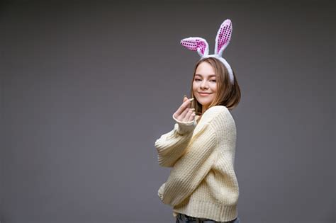 웃는 젊은 백인 소녀 토끼 귀와 금발 손가락과 회색 배경에 고립 된 카메라를보고 미니 마음을 보여줍니다 20 24세에 대한 스톡