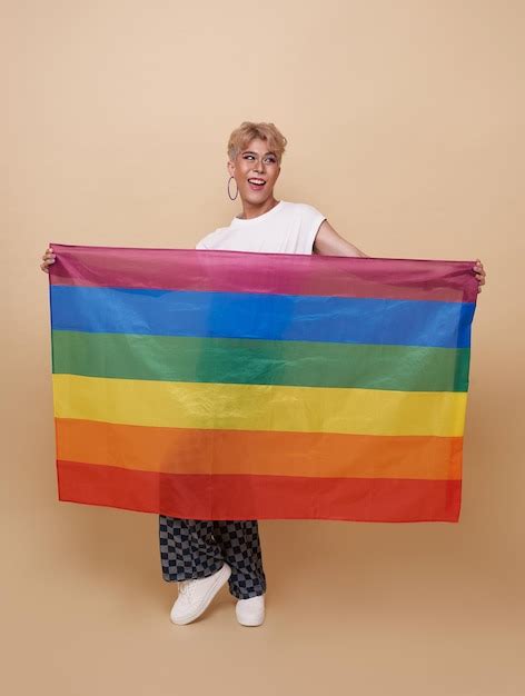 누드 색상 배경에 고립 된 무지개 깃발을 보여주는 청소년 아시아 트랜스젠더 Lgbt 프리미엄 사진