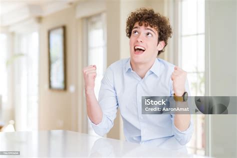 곱슬 곱슬 한 젊은 사업가는 팔을 들고 눈을 감고 성공에 놀랐고 축하하는 머리를 읽었습니다 우승자 컨셉 매우 기쁜에 대한 스톡