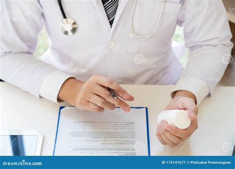 Doctor Reading On A Document Report And Writing On Paperwork And