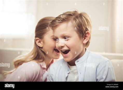Excited Brother And Sister Talking And Gossiping Together While Sitting