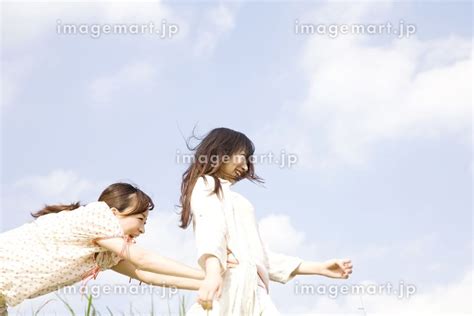 背中を友達に押される女性の写真素材 [24033182] イメージマート