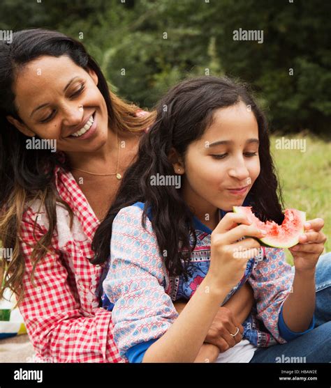 Mother And Daughter Sitting Outdoors Daughter Eating Watermelon Stock