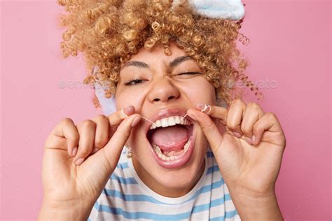 Close Up Shot Of Young Woman Cleans Teeth With Dental Floss Enjoys