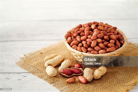 땅콩은 밝은 배경에 삼베로 덮인 테이블 위의 고리 버들 바구니에 쌓여 있습니다 구운 아라 키스 너트 더미 땅콩 더미 껍질과 전체 땅콩 매크로 땅콩 측면 보기 흰색 배경 땅콩