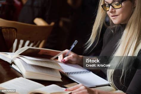 젊은 여자의 대학 학생입니다 시험을 준비 하 고 공공 도서관에서 수업을 학습입니다 교과서의 많은 수에 의해 포위 하는 테이블에 앉아 고용과 노동에 대한 스톡 사진 및 기타