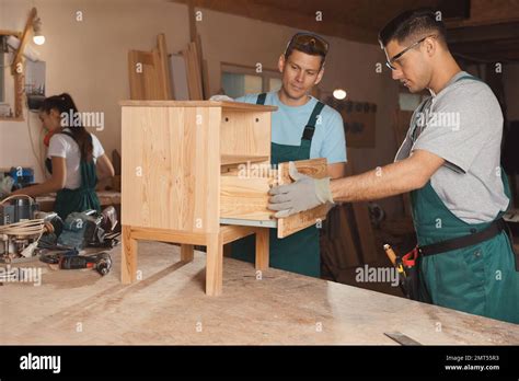 Professional Carpenters Assembling Wooden Cabinet In Workshop Stock