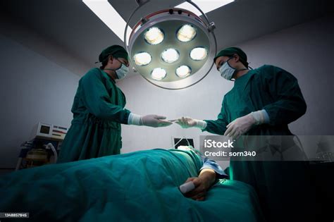 수술실에서 수술실에서 수술중인 두 명의 의사가 환자 패스 의사 집게 환자 사용 호흡보호구를 침대에 누워 있는 환자 앞의 수술용 가운 외과 의사 헤어 캡 라텍스 장갑 스탠드를