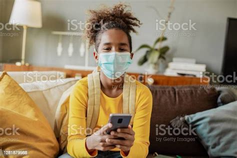 휴대 전화를 사용하여 집에서 얼굴 마스크를 가진 귀여운 아프리카 계 미국인 소녀 8 9 살에 대한 스톡 사진 및 기타 이미지