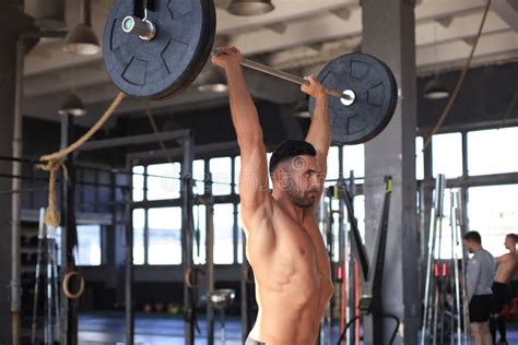 Muscular Man Working Out In Gym Doing Exercises With Barbell At Biceps